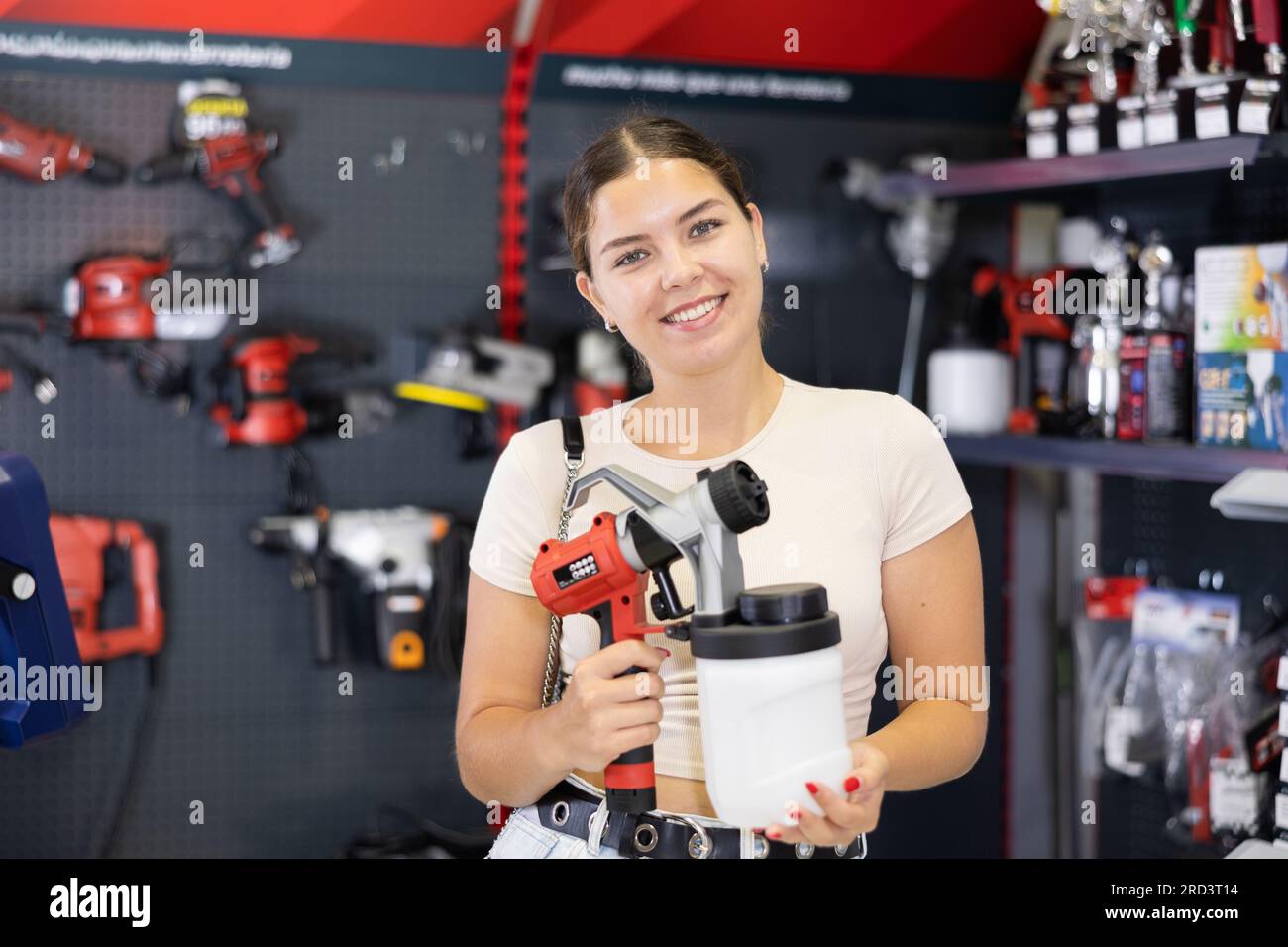 Woman choose examine handheld portable spray gun, airbrush in tools ...