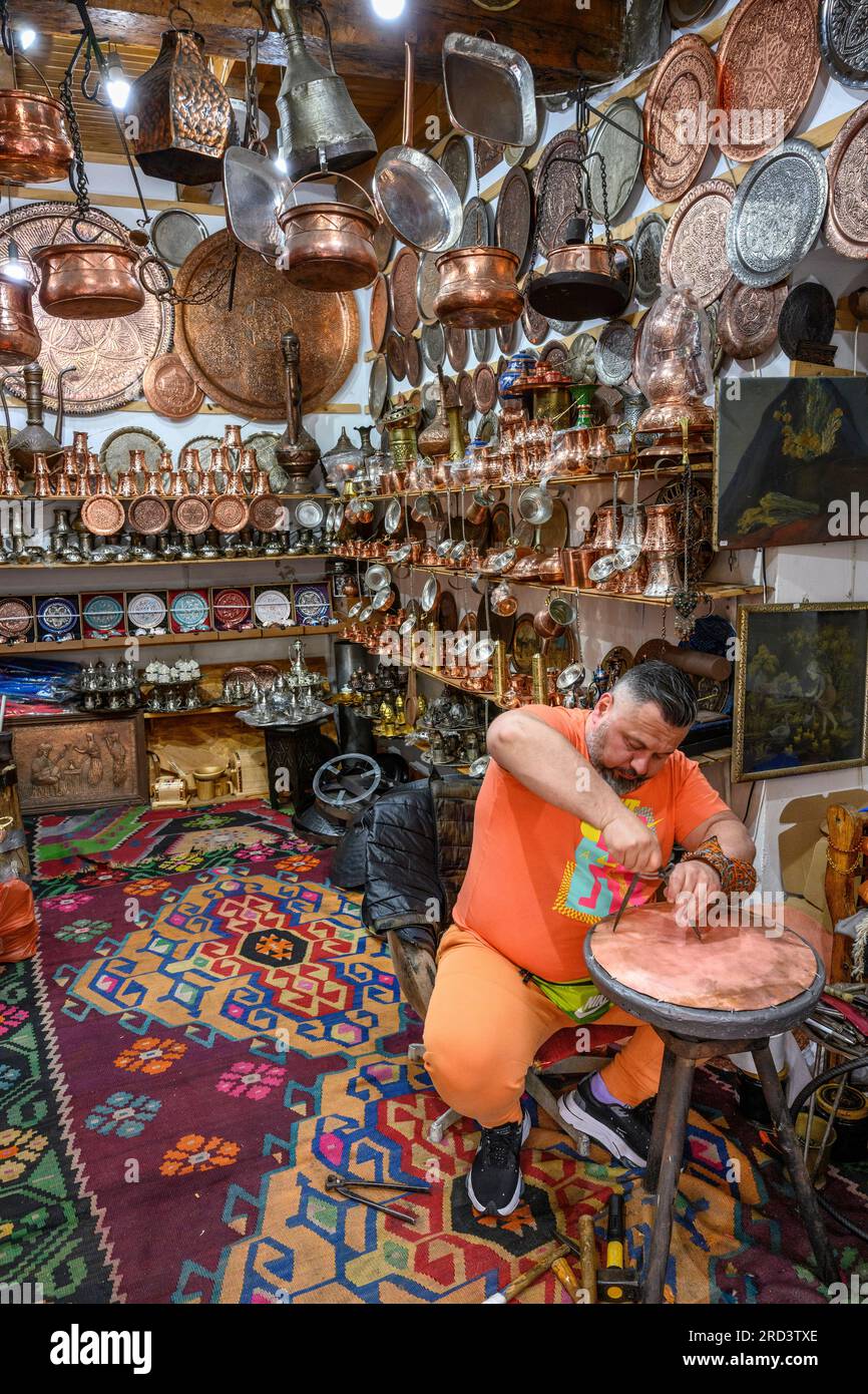 A traditional metal craftsman making copper and tin items in his shop ...