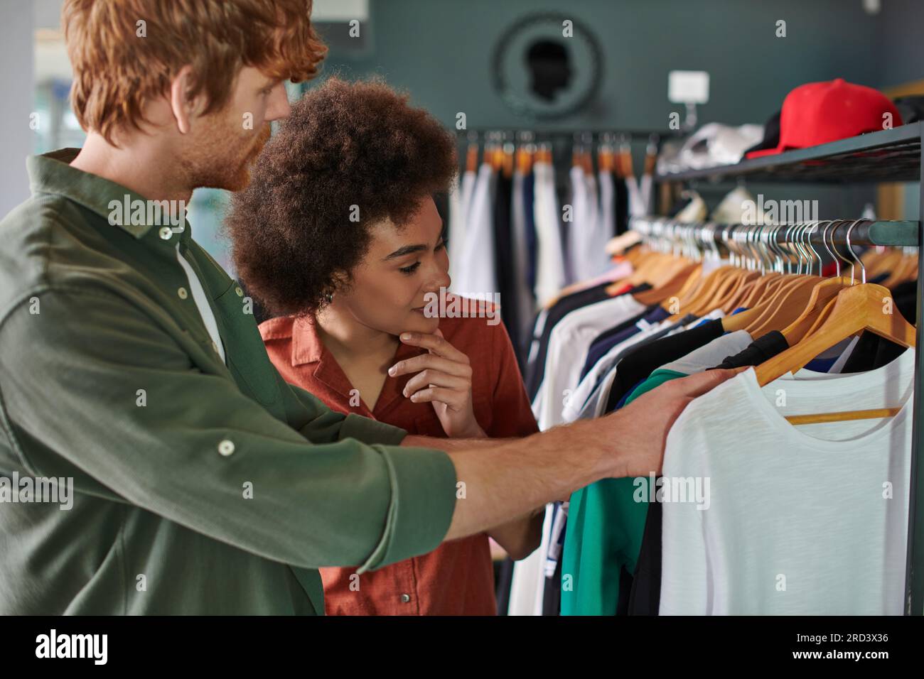Smiling young african american craftswoman looking at clothes on ...