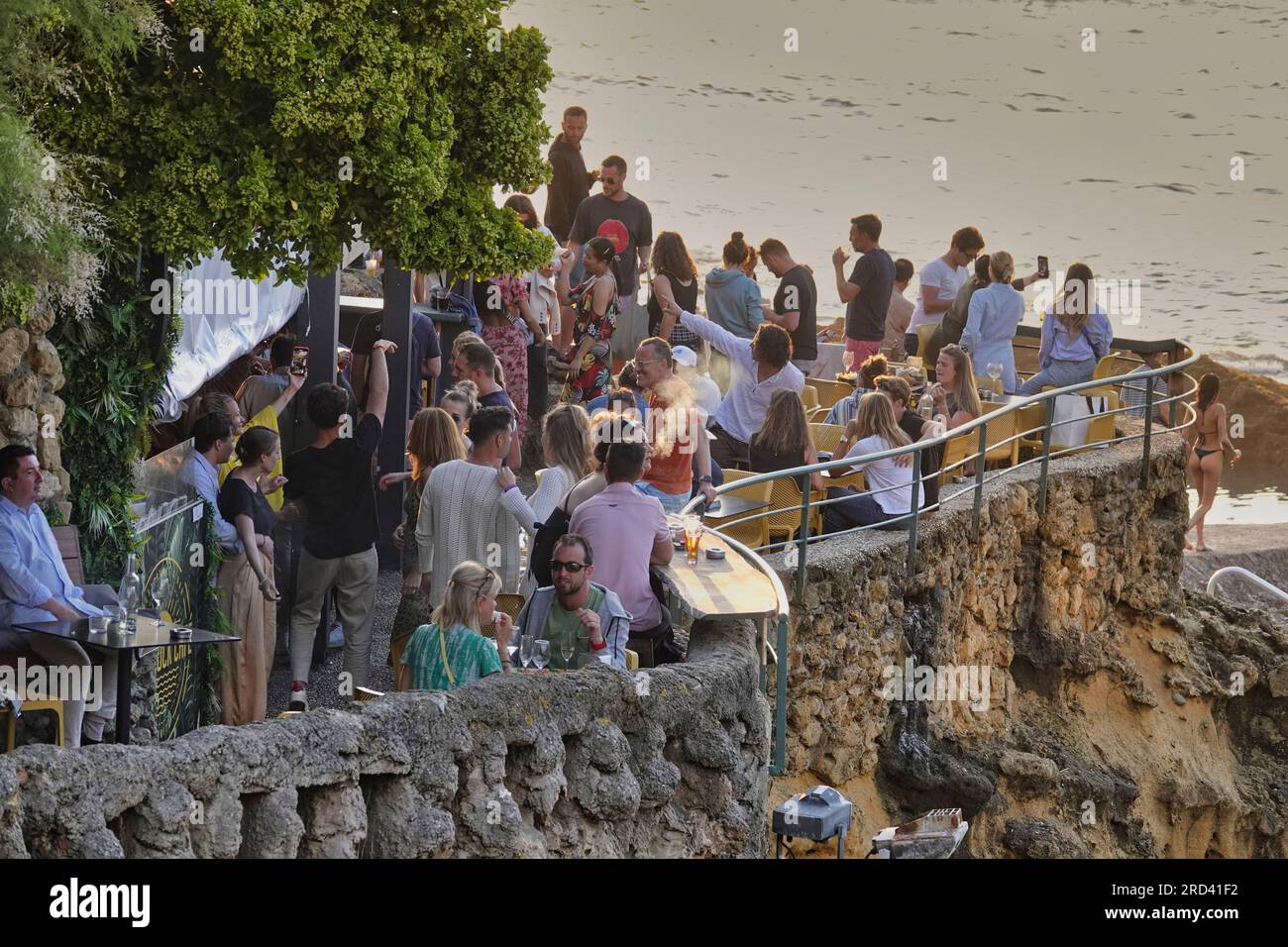 Biarritz, France, July, 2023 As the sun goes down revellers meet at the ...