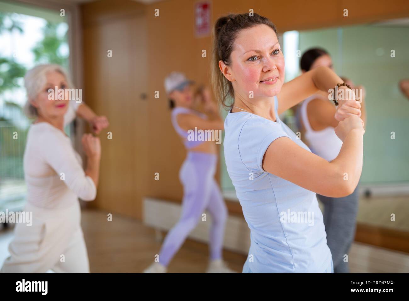 Four active women of different ages performing energetic moves of hands ...
