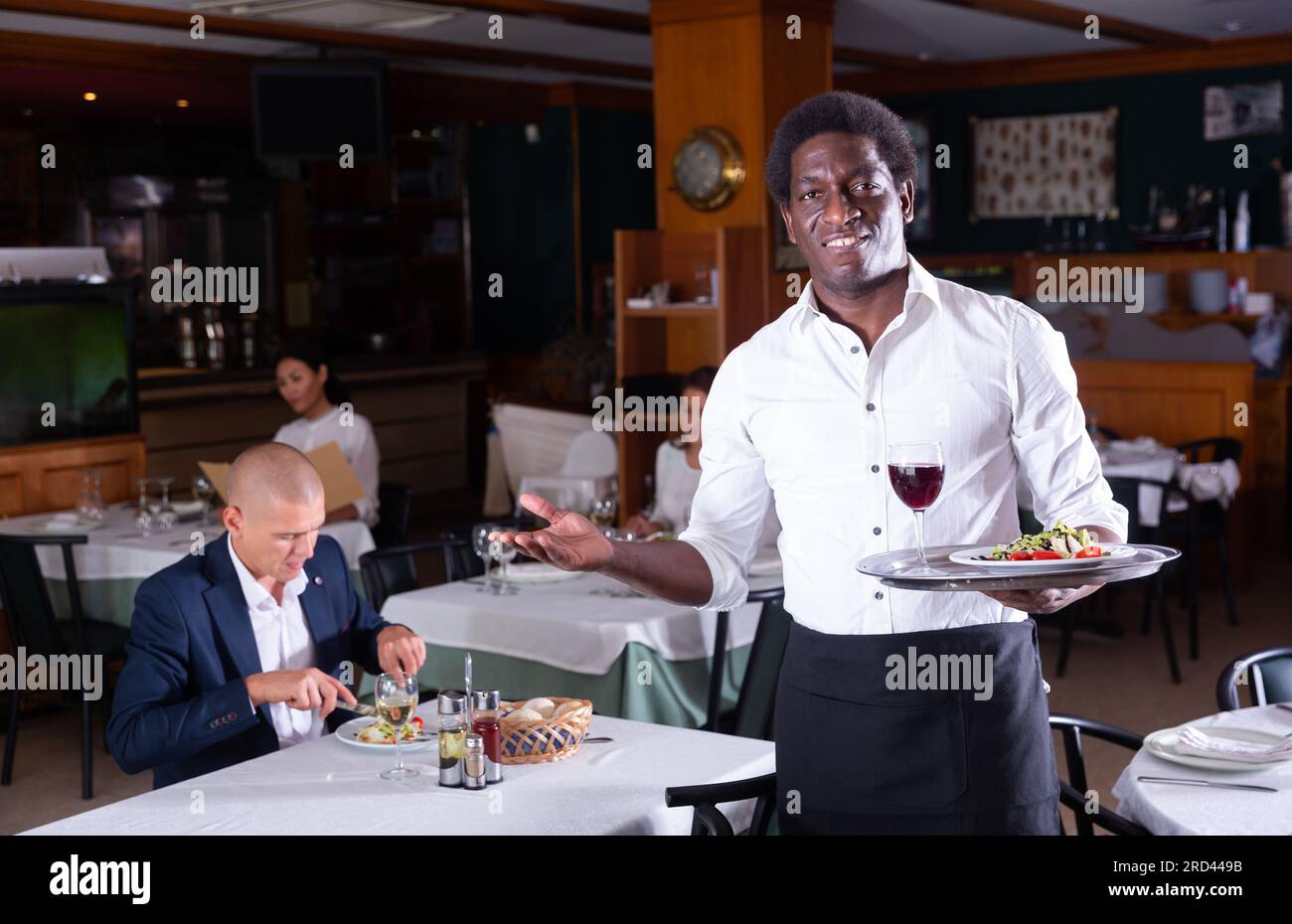 Hospitable african american waiter greeting guests in restaurant Stock ...