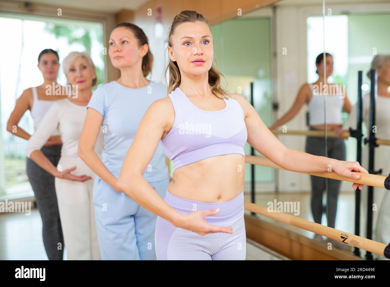 Female ballet instructor adjusting students form in dancing school ...