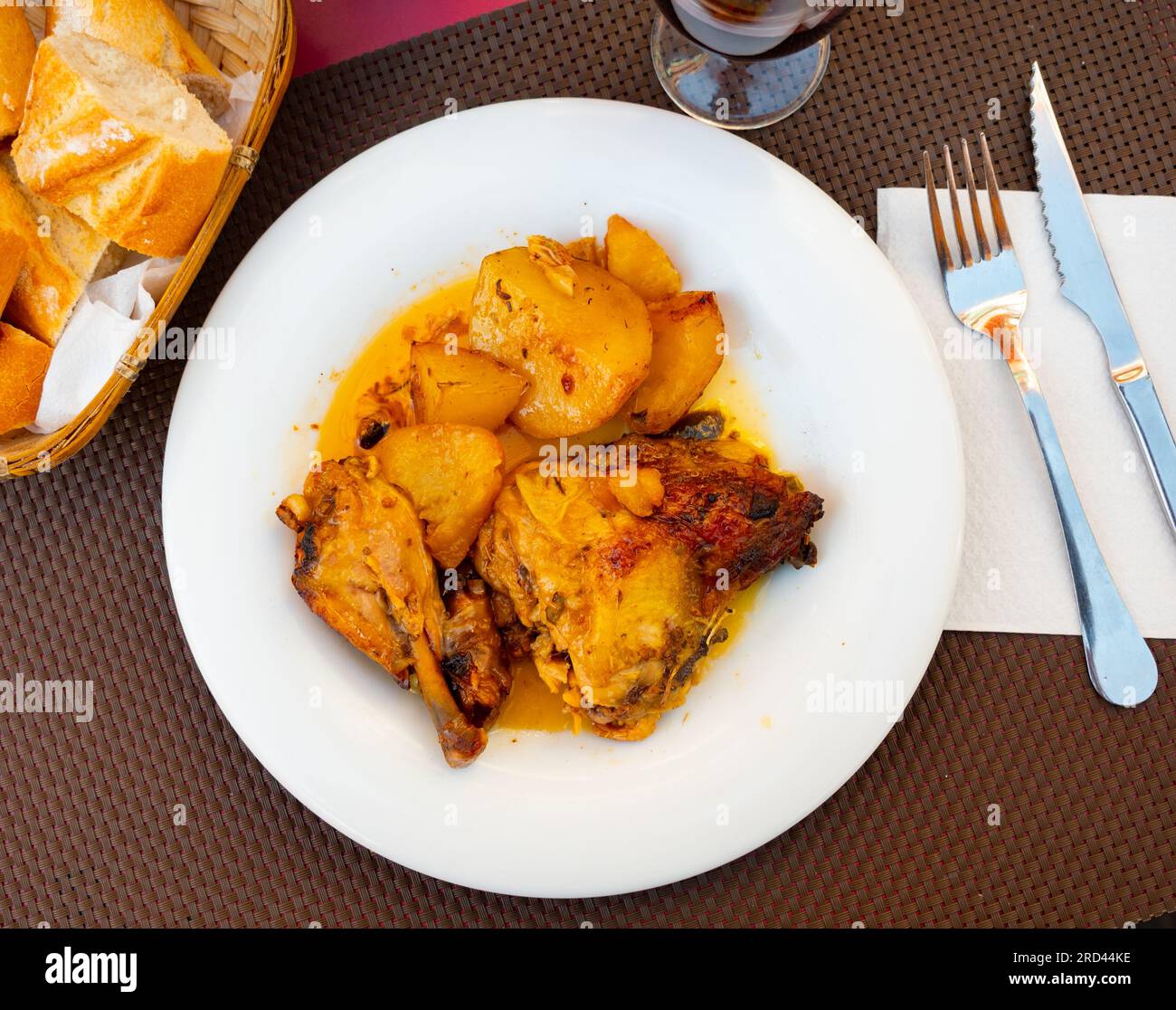 Baked chicken leg served on plate with side dish of fried potatoes ...