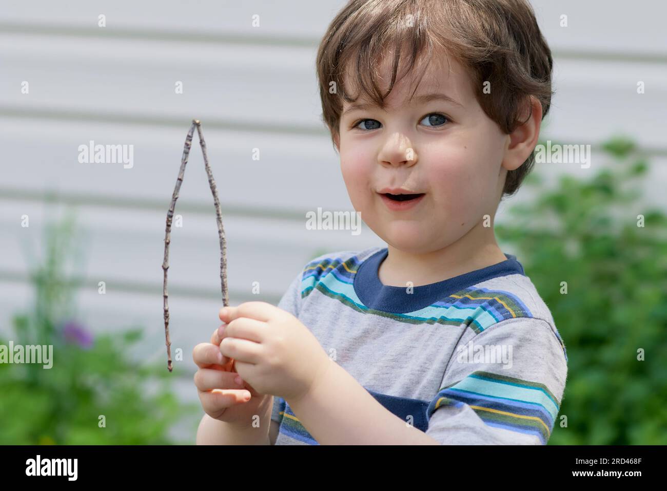 Cute baby boy playing with a stick in the backyard Stock Photo - Alamy