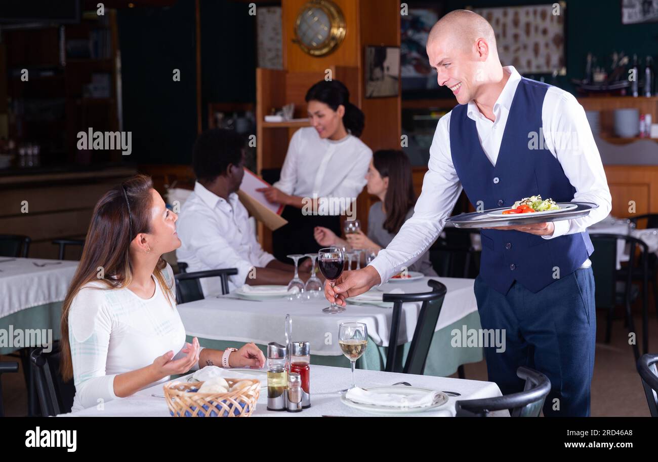 Polite waiter serving young female guest of restaurant Stock Photo - Alamy