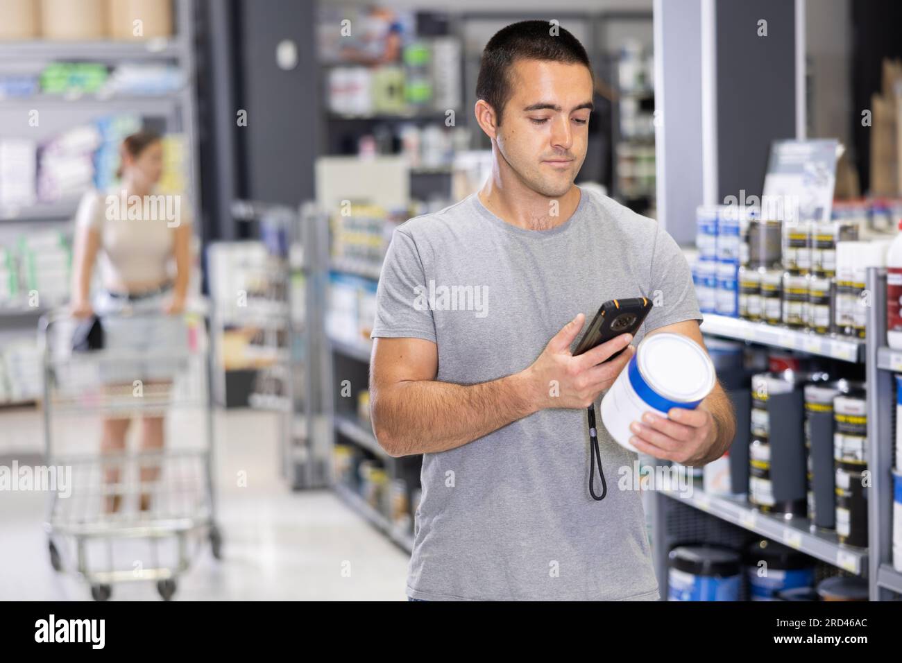 Male shopper scanning a QR code using a mobile phone in hardware store ...