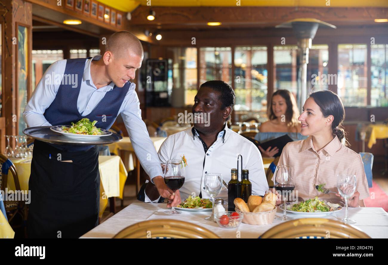 Elegant waiter serving company at restaurant Stock Photo - Alamy