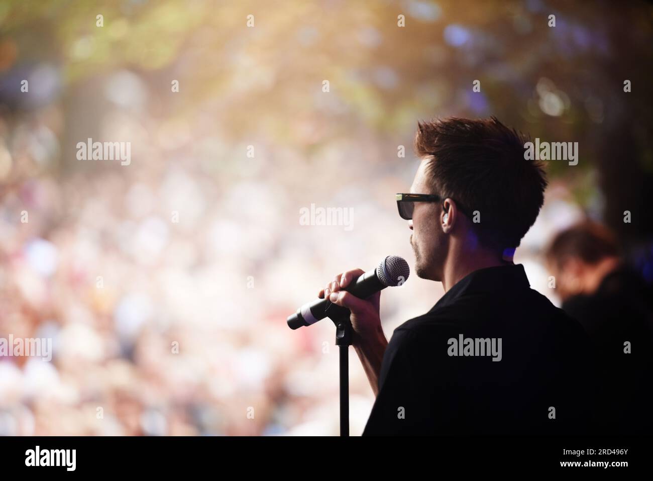 Charismatic frontman. A singer performing on stage at an outdoor music ...