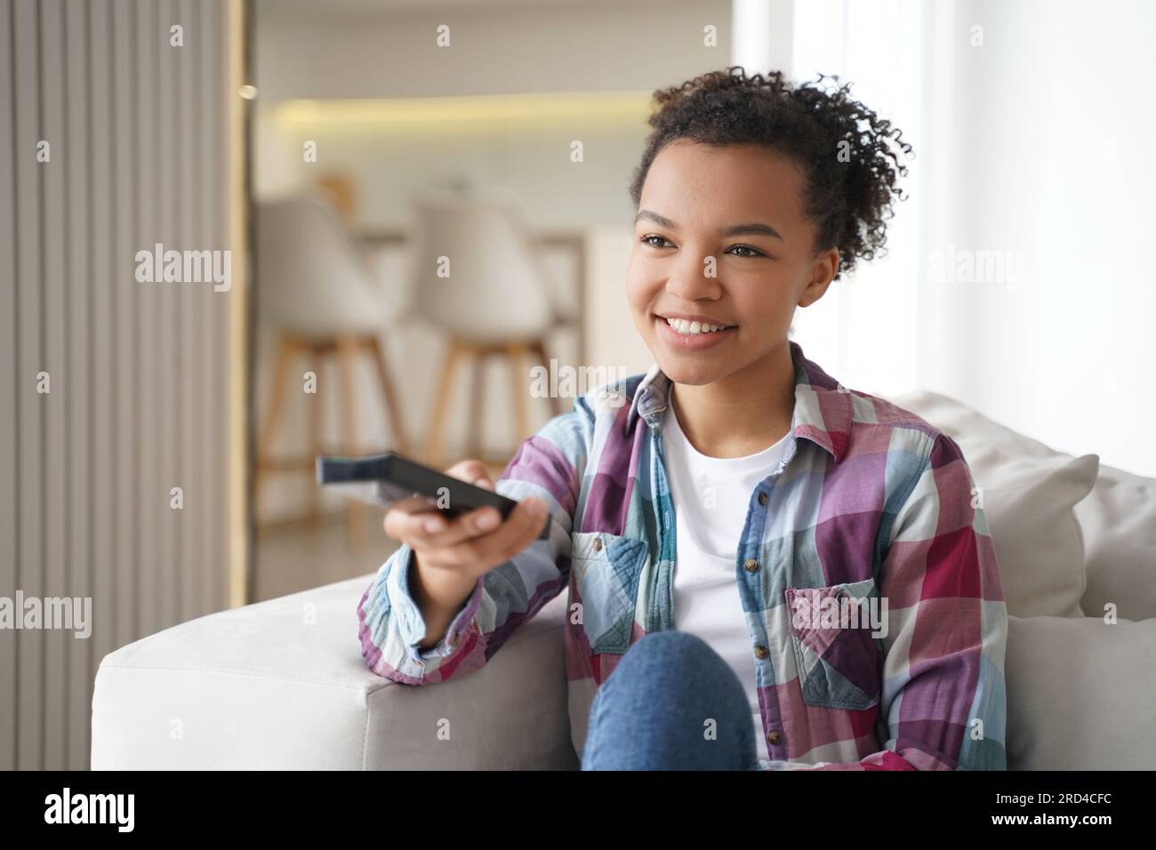 Joyful girl switches TV channels, enjoying leisure on the sofa Stock ...