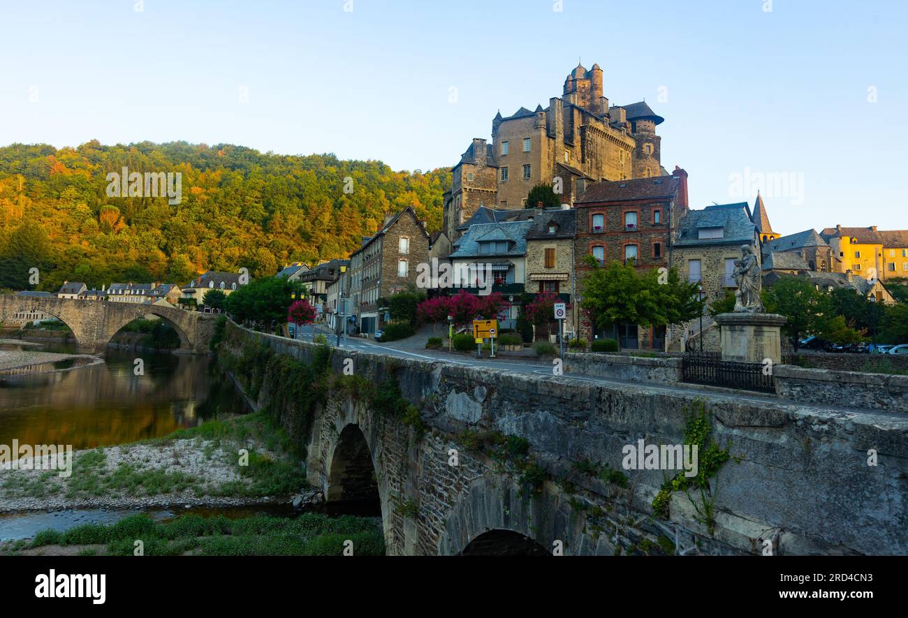 French township of Estaing on bank of Lot River with arched bridge and ...