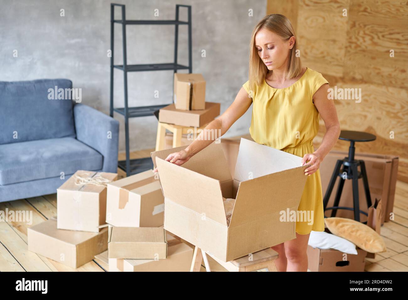 Young girl packing plates into the boxes ready to move. Woman unpacking ...