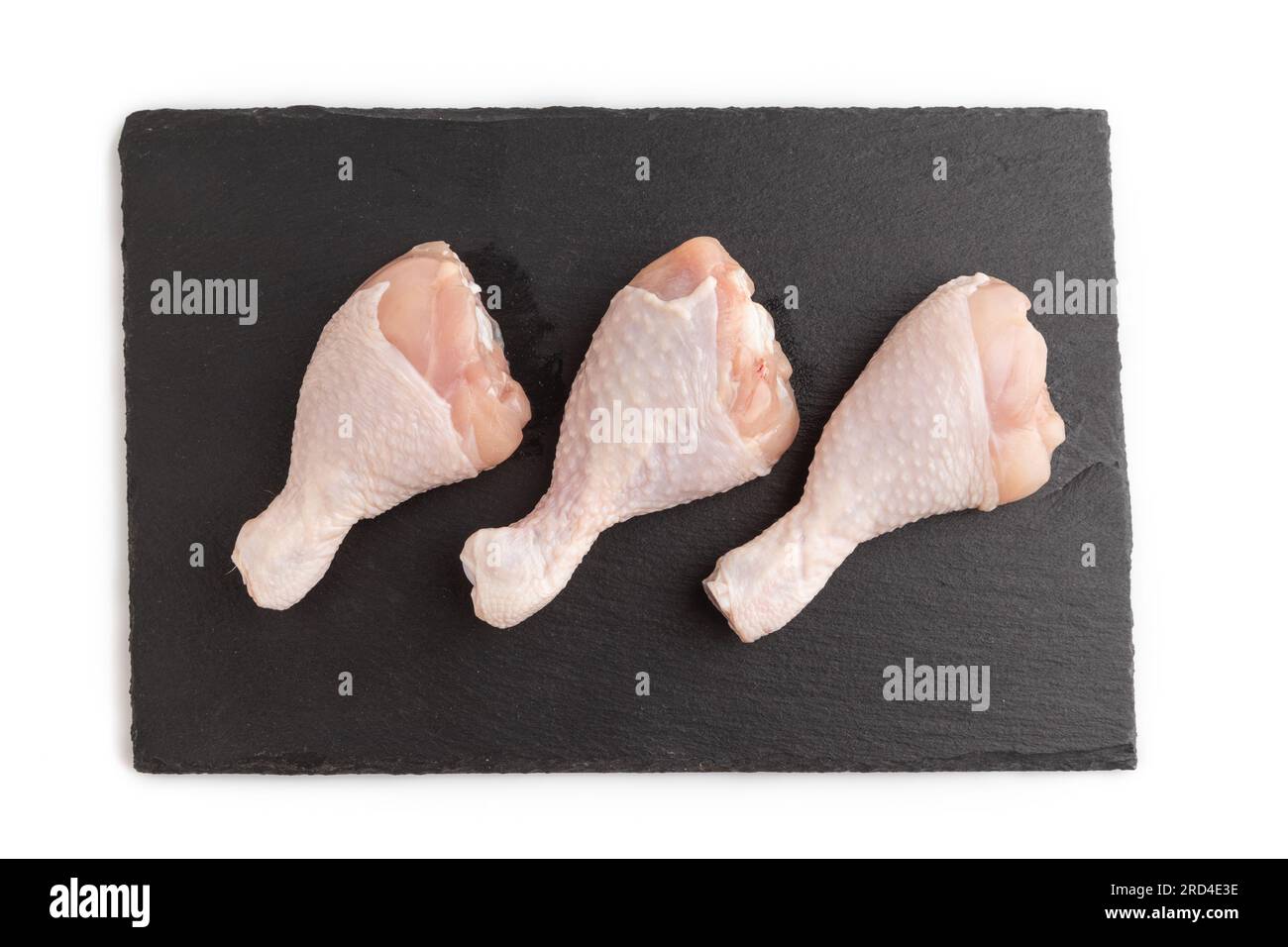 Raw chicken legs on a black slate cutting board isolated on white ...
