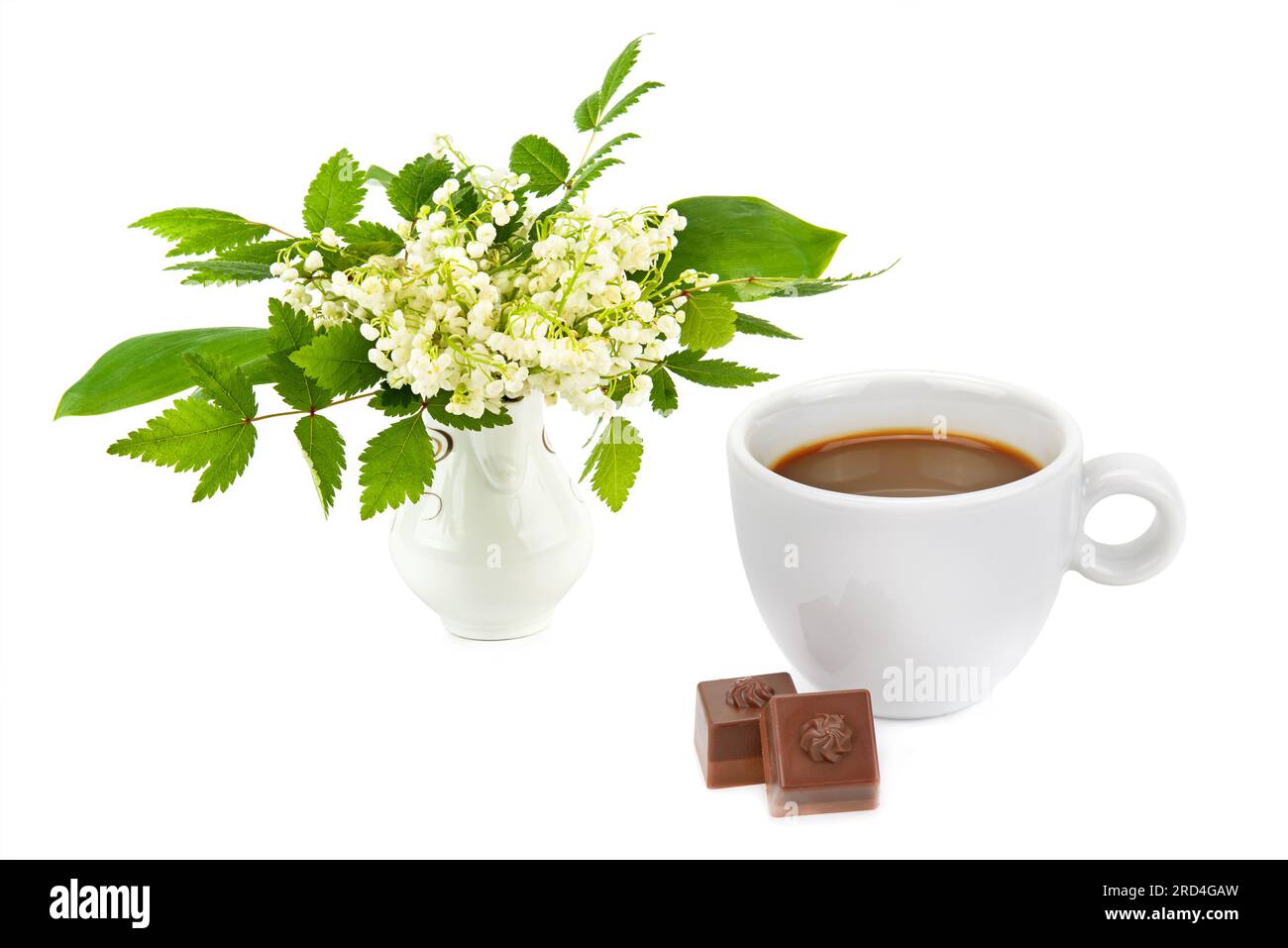 A cup of coffee and a bouquet of lilies of the valley in a vase ...