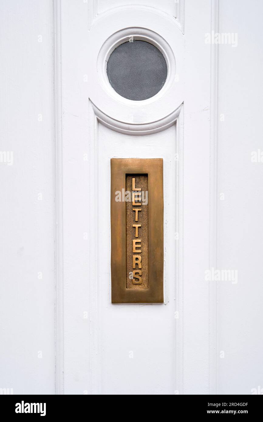 White painted door with vertical brass letter box and small round ...