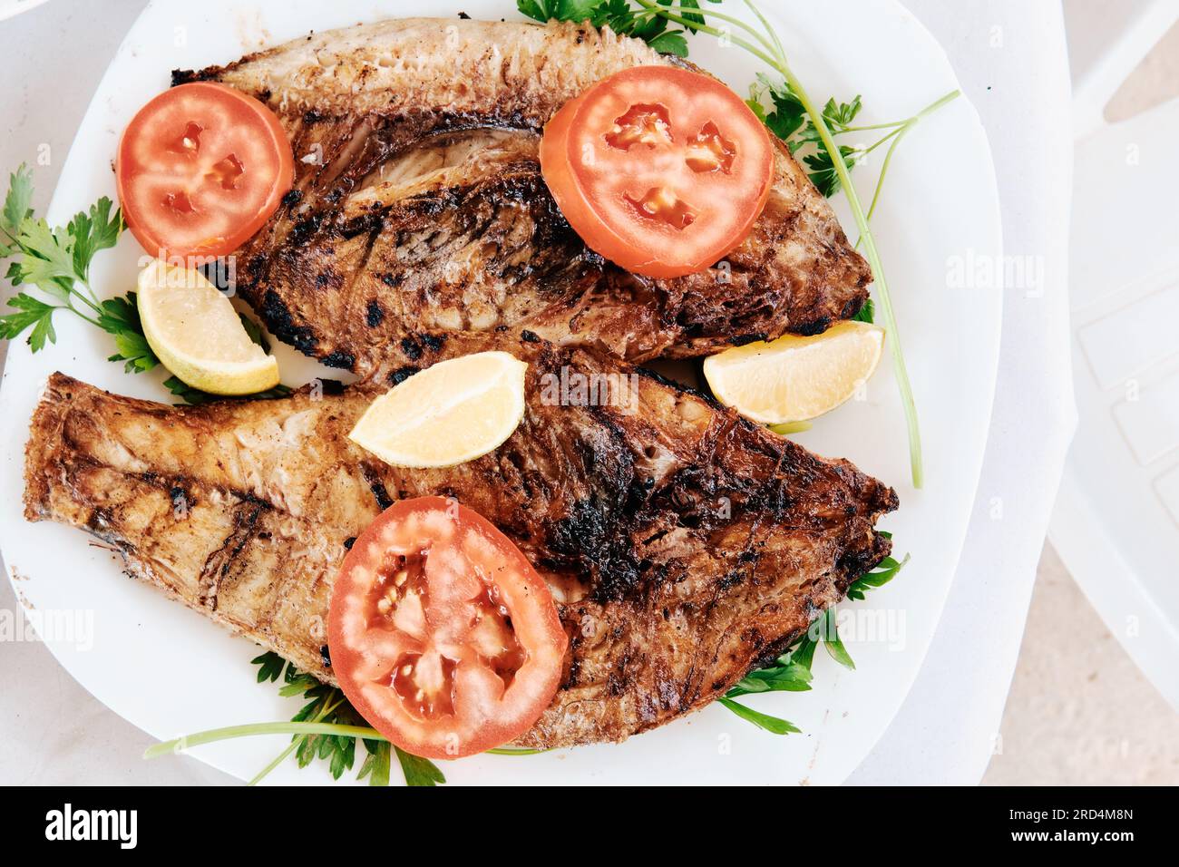 Tilapia fish grilled with tomato herb and lemons Stock Photo - Alamy