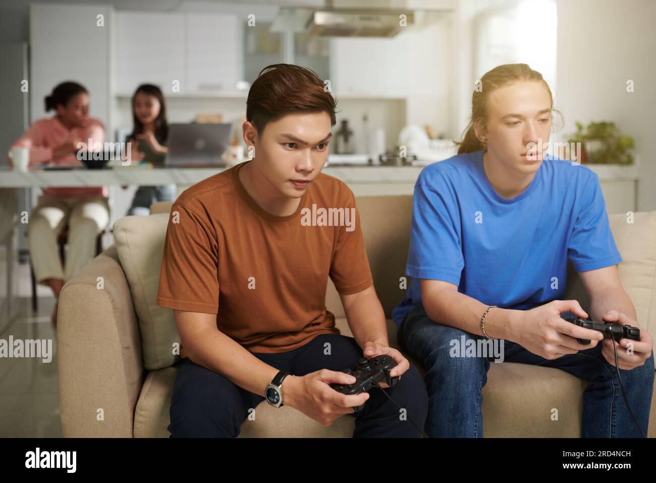 Serious teenage boys playing videogames at home when their friends ...
