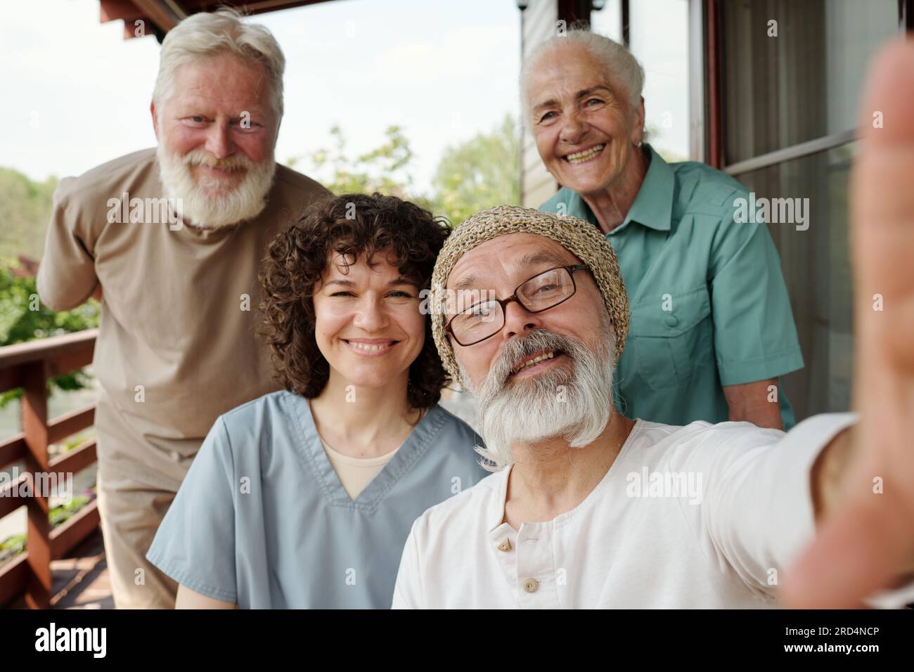 Happy young caregiver and group of senior people making selfie on ...