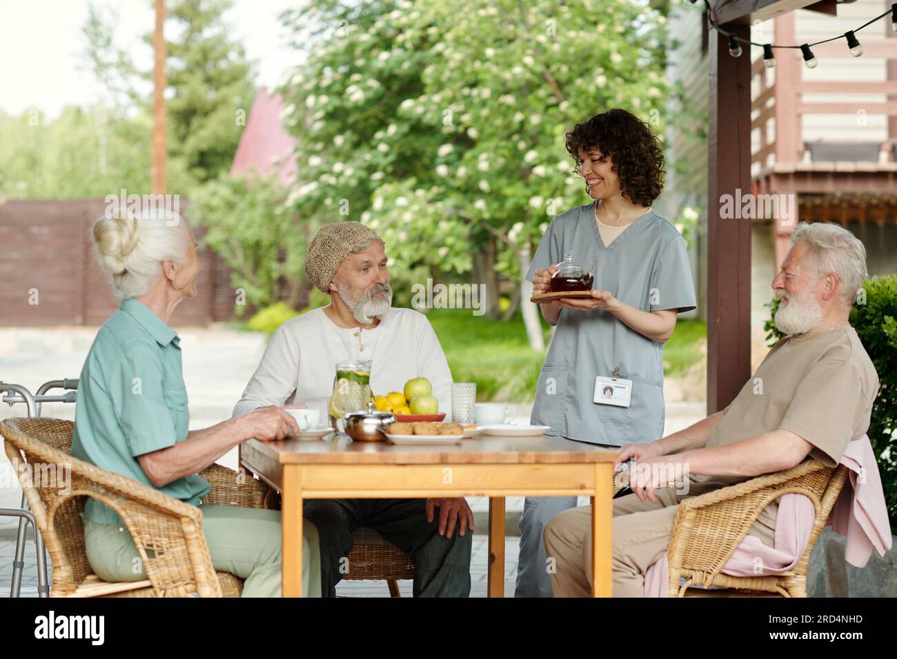 Happy young nurse in uniform brought teapot with herbal tea for ...