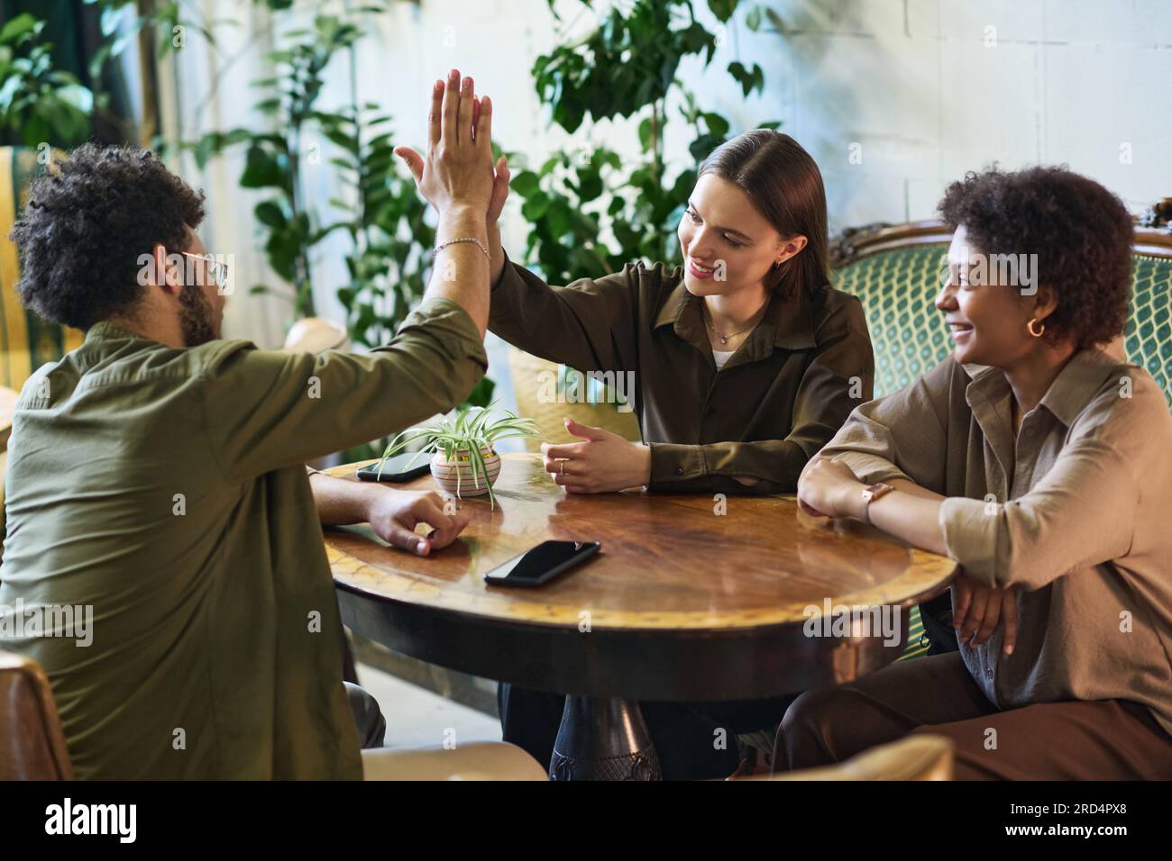 Happy young woman giving high five to her boyfriend sitting in front of ...