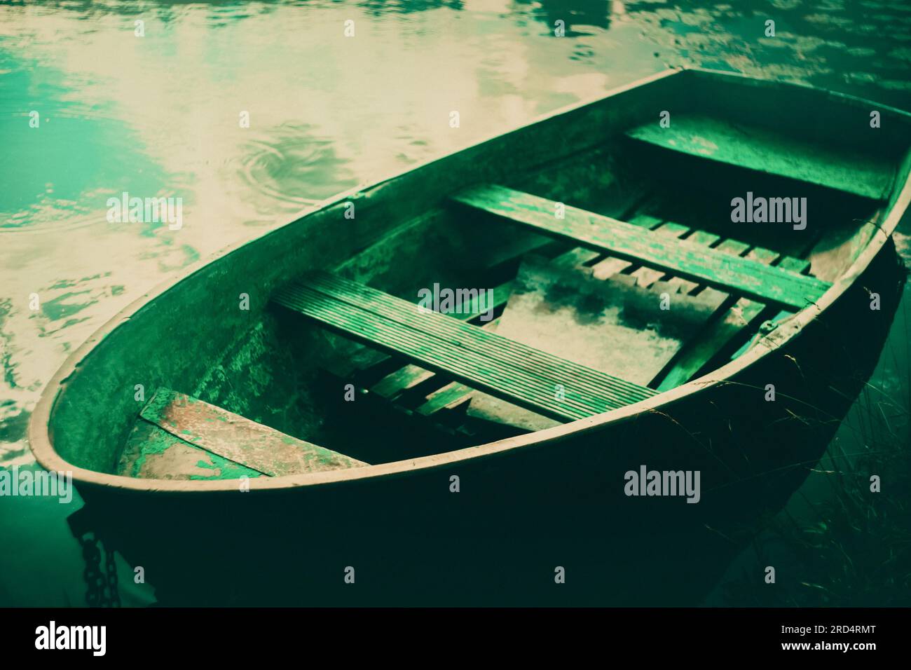 An old wooden boat floating by the riverbank on a summer day ...