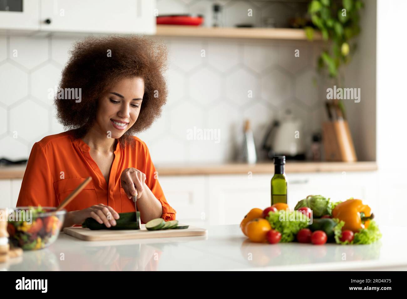 Portrait of happy black woman cooking healthy lunch in kitchen interior ...