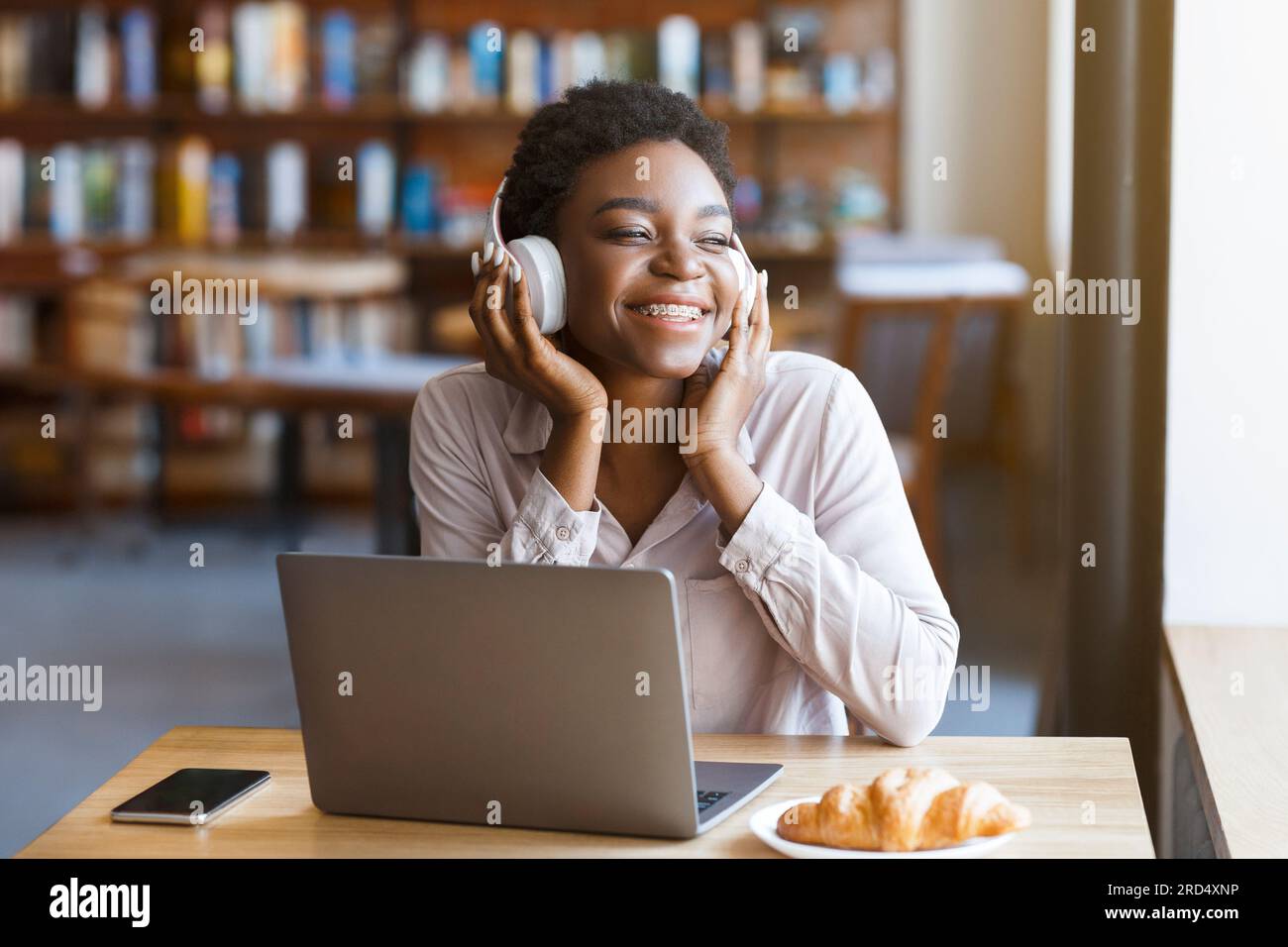 Black woman listening to music with headset, laptop in cafe Stock Photo ...