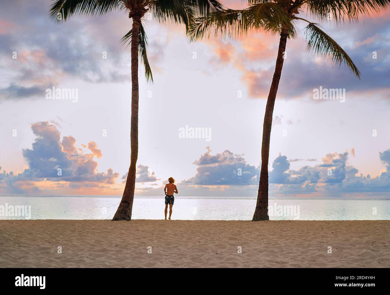 Running teenage boy between tall palm trees on Flic en Flac beach with ...