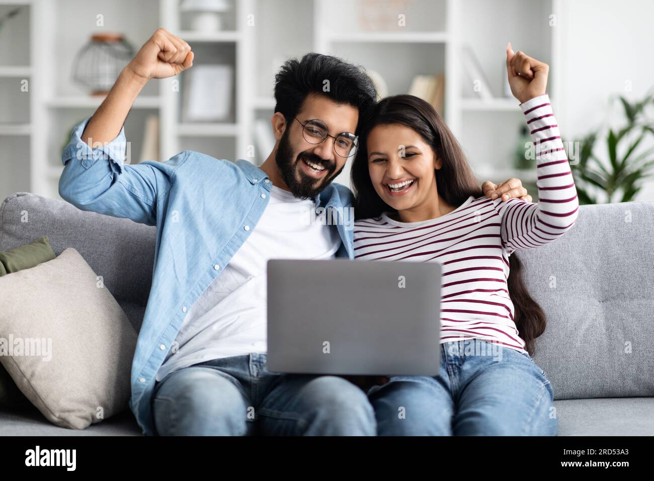 Emotional indian couple using computer at home, celebrating success ...