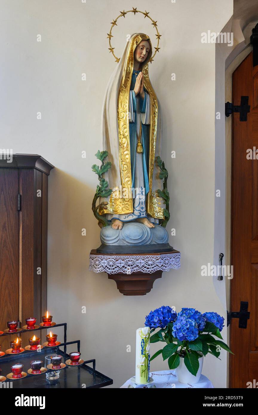 Figure of the Virgin Mary with sacrificial lights and floral decoration ...