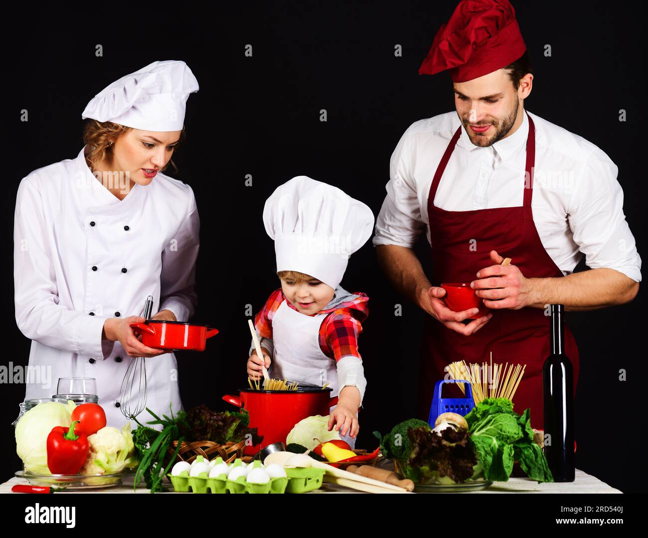 Happy family in chef uniform cooking at home. Family preparing healthy ...