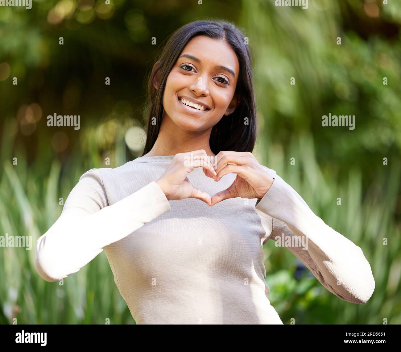 Portrait, smile and woman with heart hands in nature for love, care and ...
