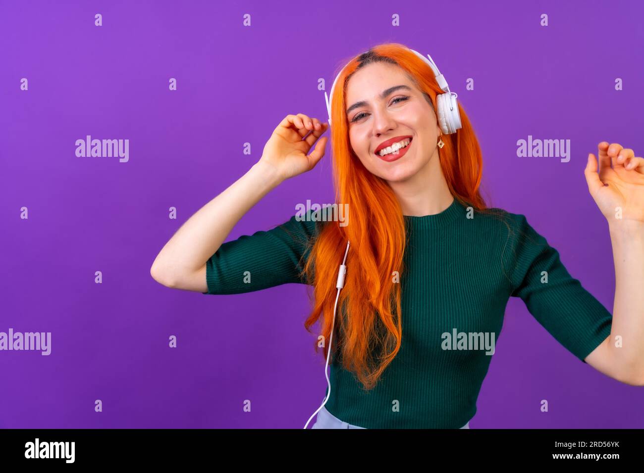 Redhead woman in studio photography smiling dancing on a purple ...