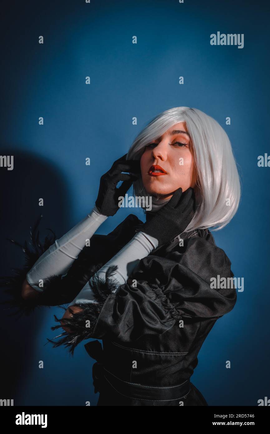 Portrait of cosplay woman in a black costume and a white wig in studio ...