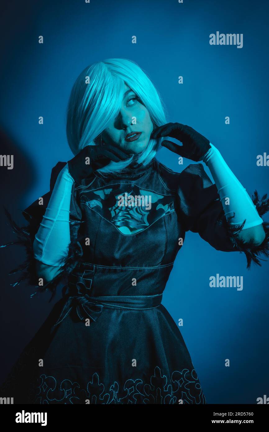 Portrait of cosplay woman in black costume and a white wig in studio ...