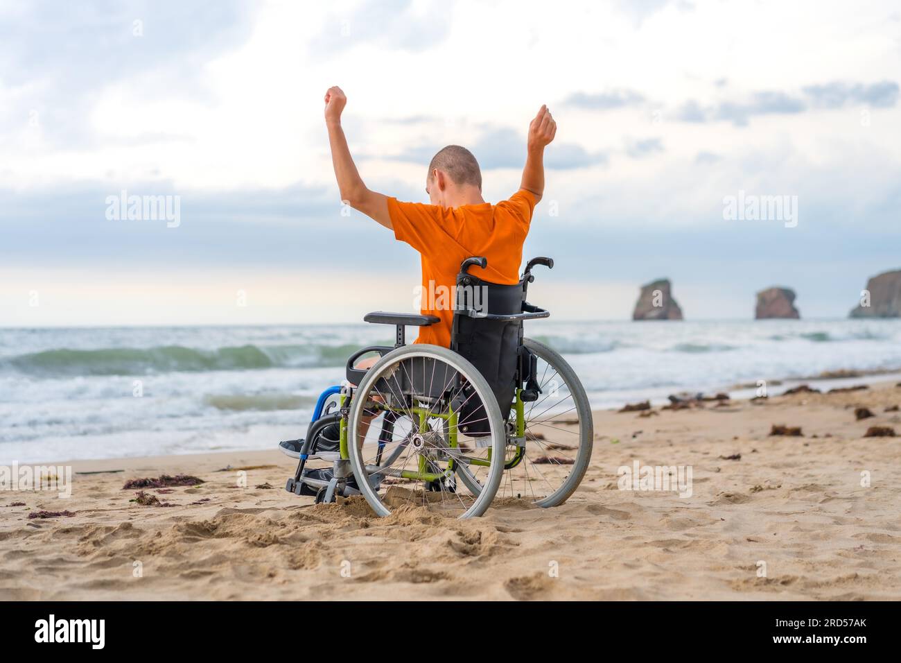A disabled person on his back in a wheelchair on the beach with open ...