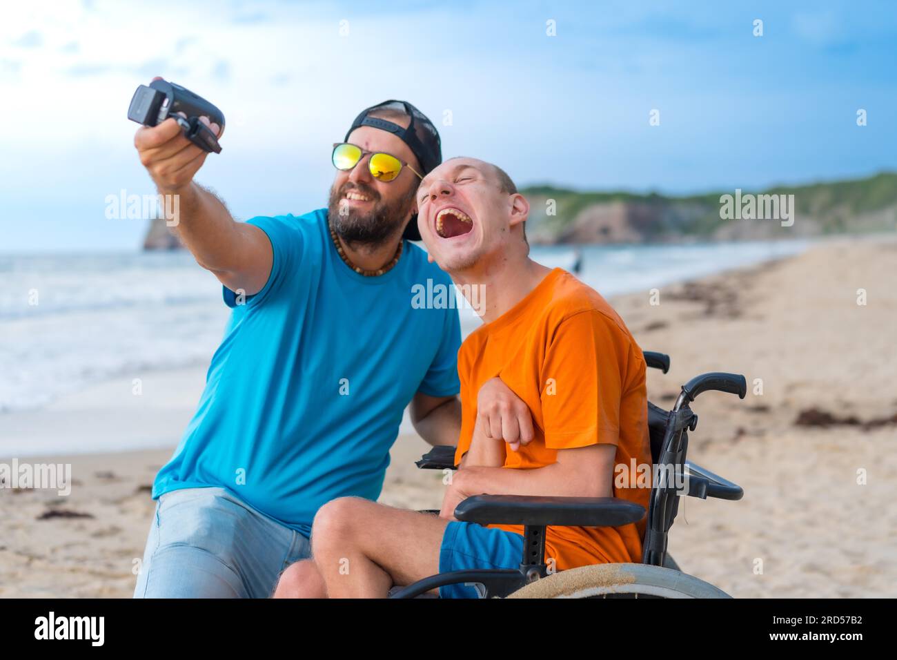 A disabled person in a wheelchair on the beach with a friend having fun ...