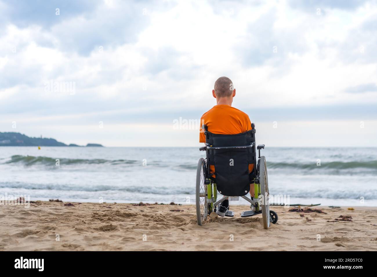 A disabled person on his back in a wheelchair on the beach in summer ...