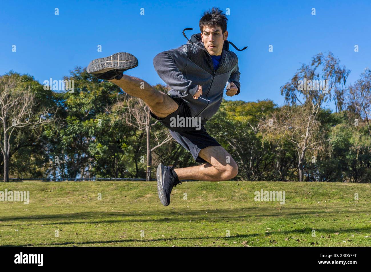 Martial arts fighter jumping in fly wearing sportswear in a public park ...