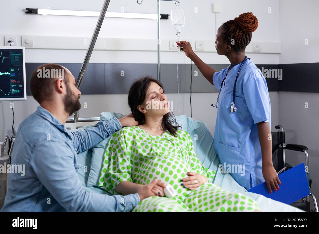 African american nurse checking pregnant woman iv drip, preparing for ...