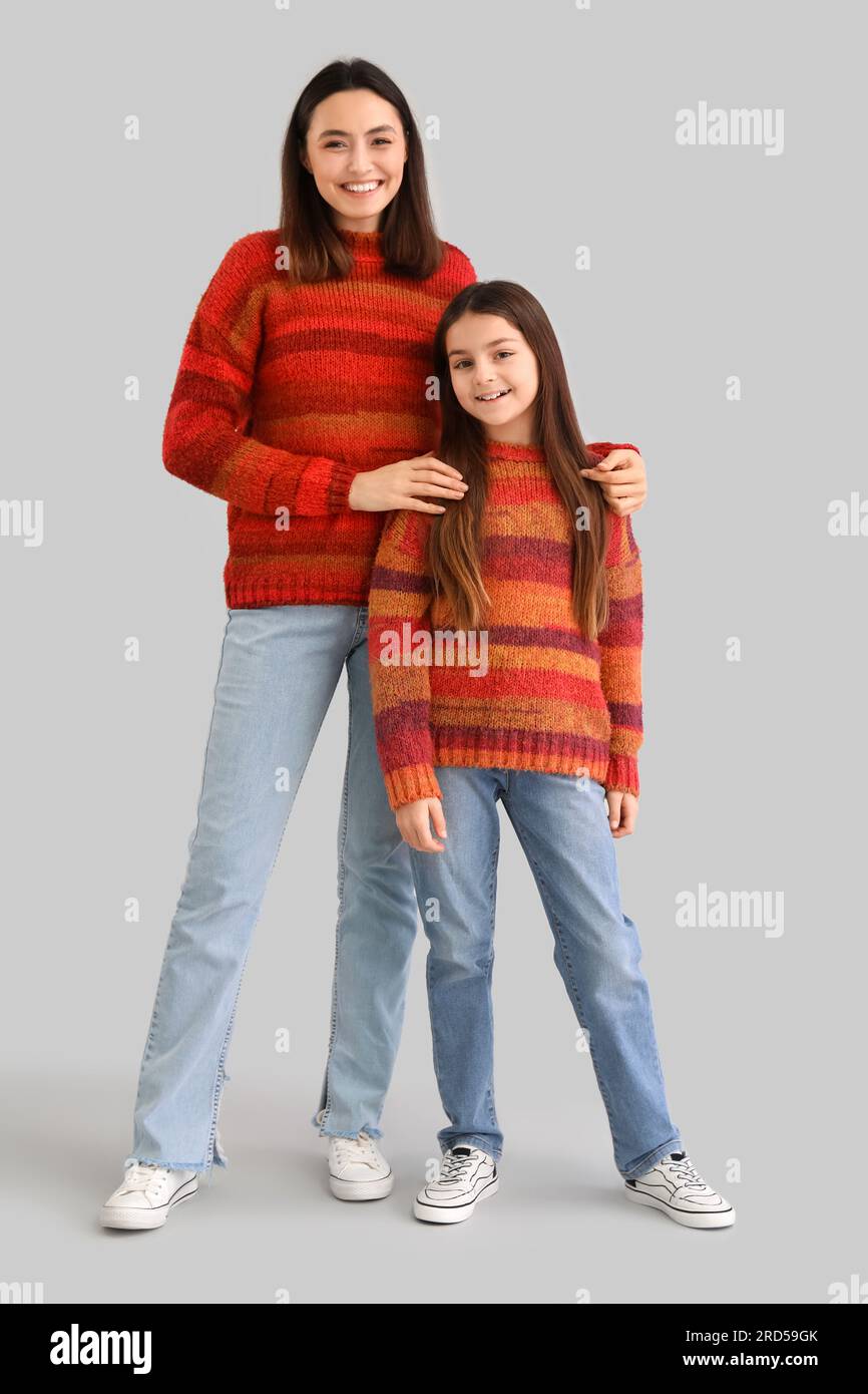 Little girl and her mother in warm sweaters on grey background Stock ...