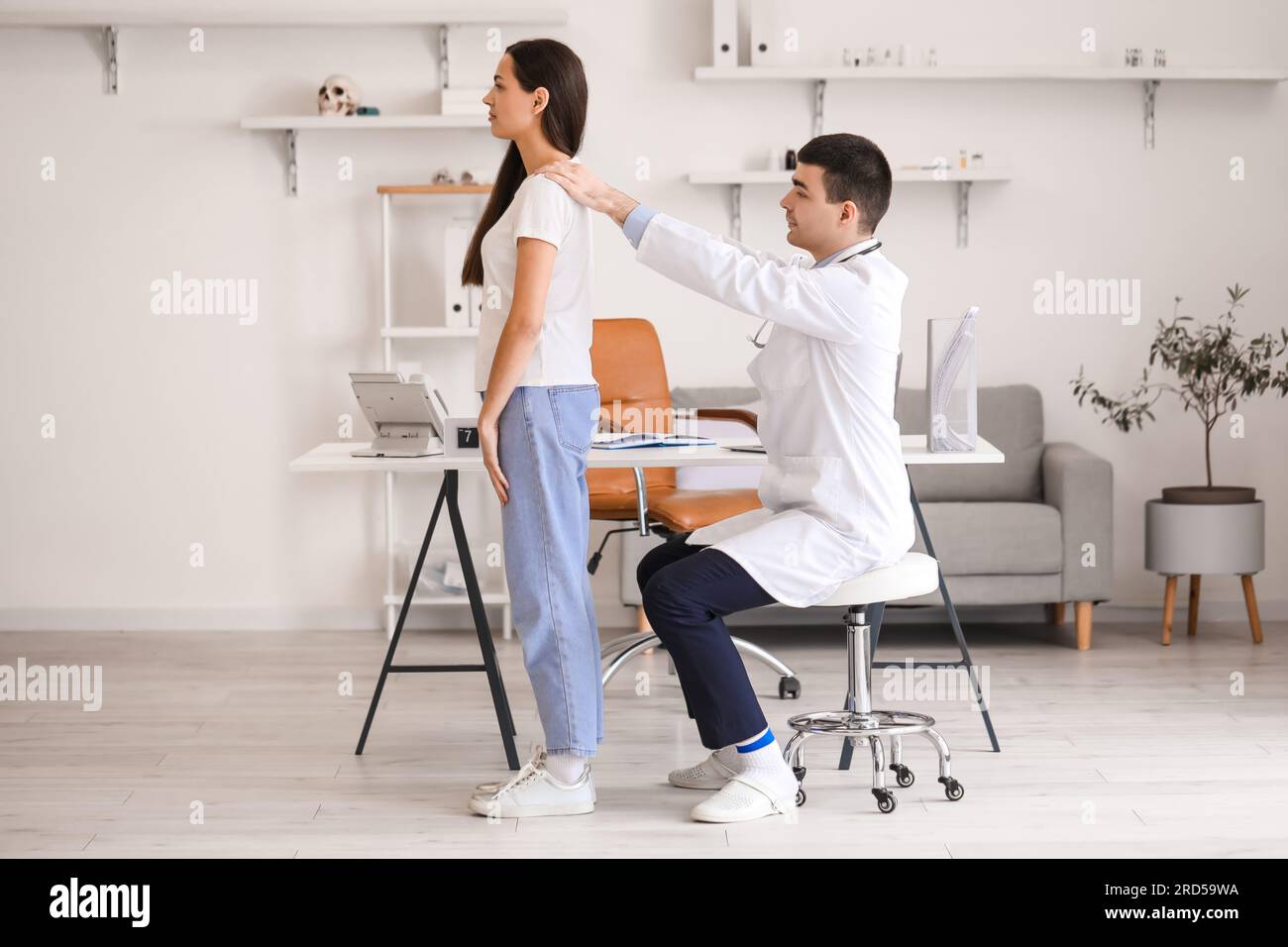 Male doctor checking posture of young woman in clinic Stock Photo - Alamy