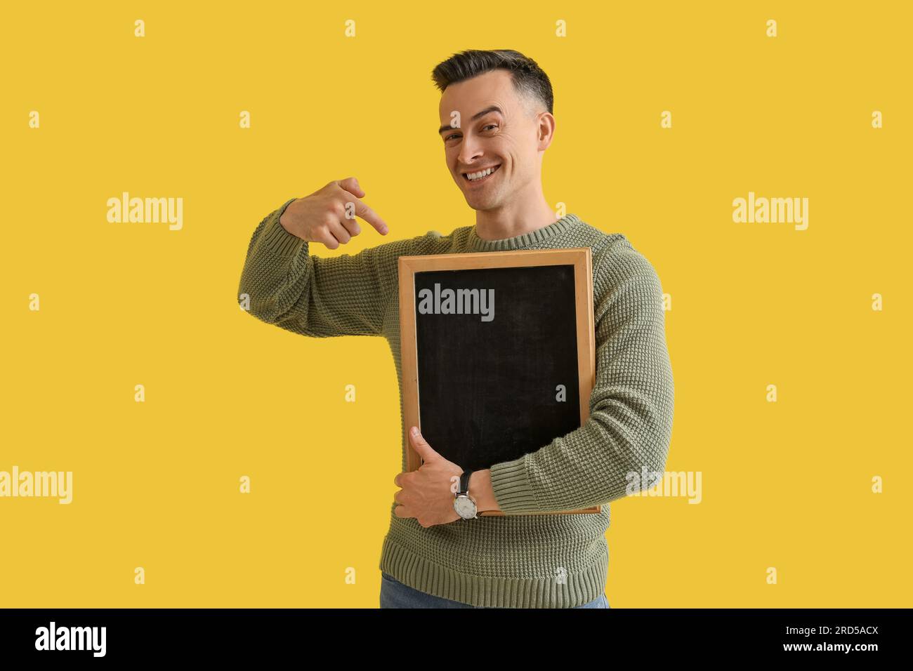Male teacher pointing at chalkboard on yellow background Stock Photo ...
