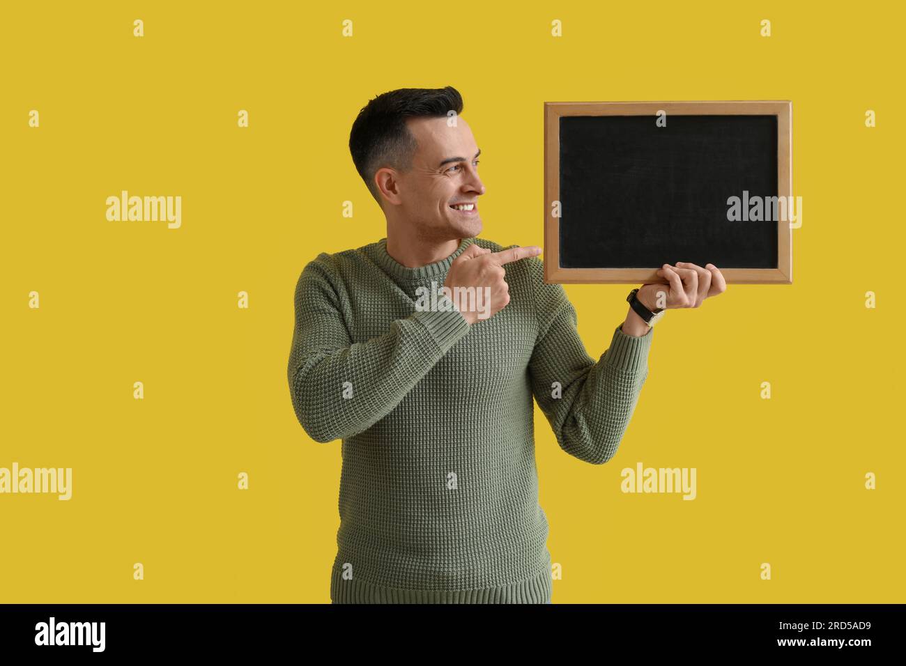 Male teacher pointing at chalkboard on yellow background Stock Photo ...