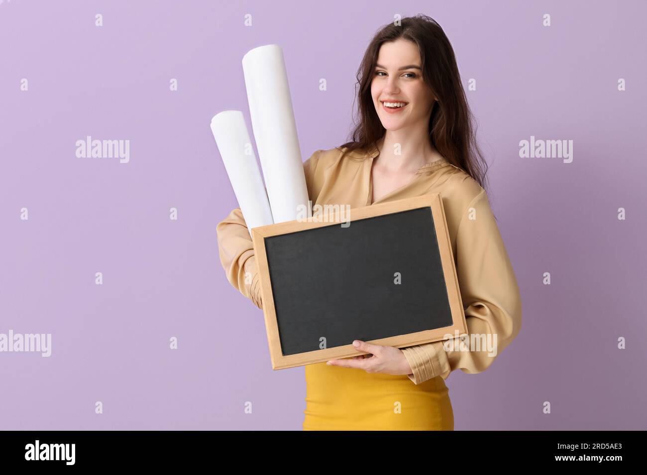 Female teacher with chalkboard and paper rolls on lilac background ...