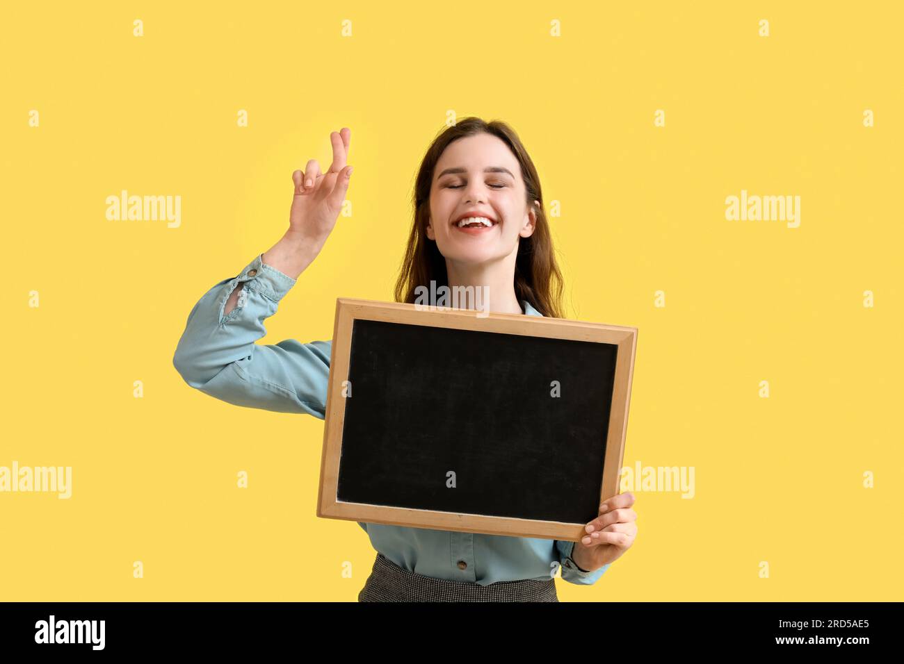Female teacher with chalkboard pointing at something on yellow ...