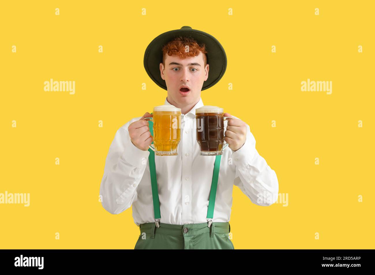 Shocked young man in traditional German clothes with beer on yellow ...