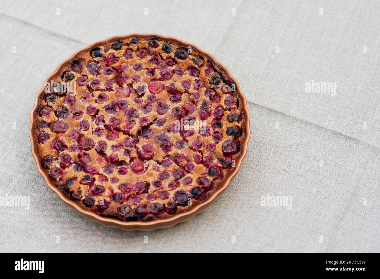 Delicious cherry clafoutis in round baking dish on light background ...