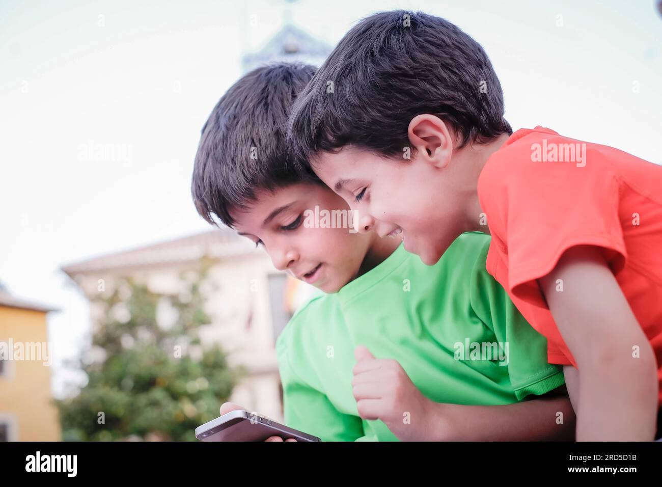 two young boys having fun sending messages with a mobile phone, two ... two young boys having fun sending messages with a mobile phone, two ...