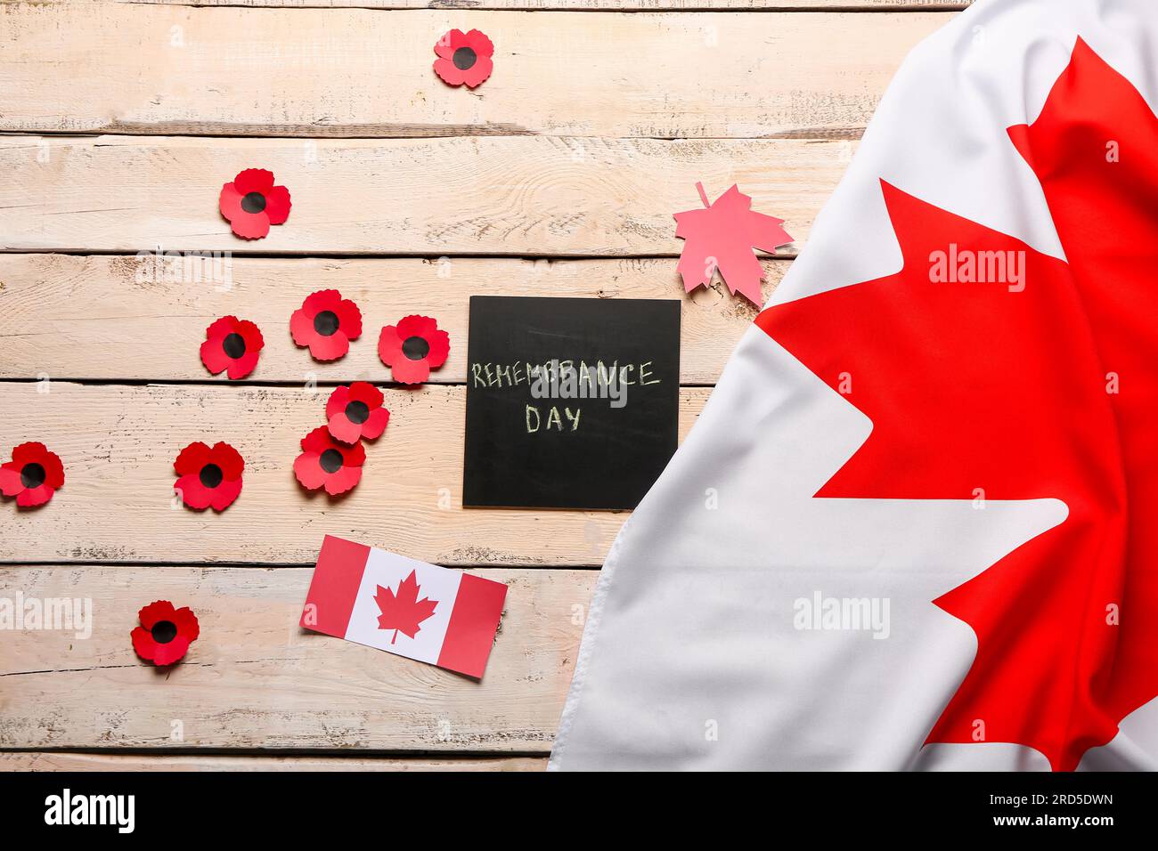 Poppy flowers with flags of Canada and card on beige wooden background ...